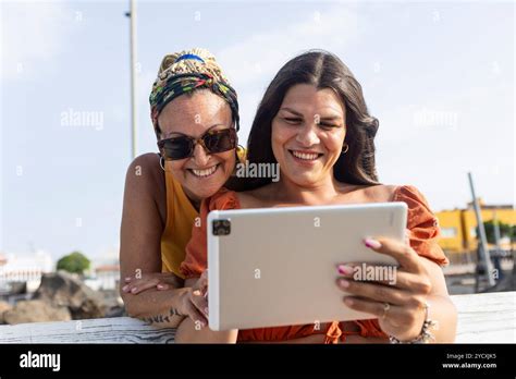 A Mother And Her Transgender Daughter Enjoy A Sunny Day Together Smiling As They Share Content