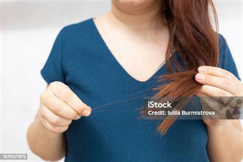 파란 셔츠를 입은 알아볼 수 없는 긴 빨간 머리 여자는 손에 머리카락을 잔뜩 들고 하얀 스튜디오에서 머리 아이템 하나를 돌린다 35 39세에 대한 스톡 사진 및 기타 이미지