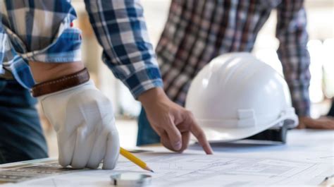 Construction Workers Reviewing Blueprints With Pencil And Compass