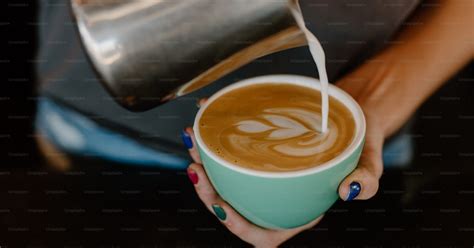 한 여자가 커피 한 잔을 따르고 있다 사진 Unsplash의 호박 스파이스 라떼 이미지