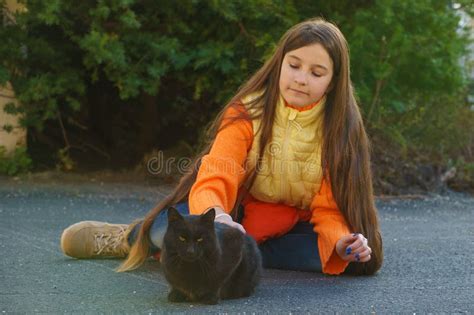 Linda Chica Masticando Un Gato Negro Mientras Se Sienta En La Calle Foto De Archivo Imagen De