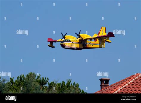 Yellow Firefighting Airplane Flying Low Over Residential Area With A Clear Blue Sky In The