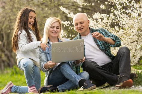 Grandfather Granddaughter And Daughter With Laptop In The Garden Stock