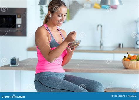 Uma Jovem Sorridente Comendo Cereais Com Morangos Enquanto Se Senta Na Cozinha Em Casa Foto De