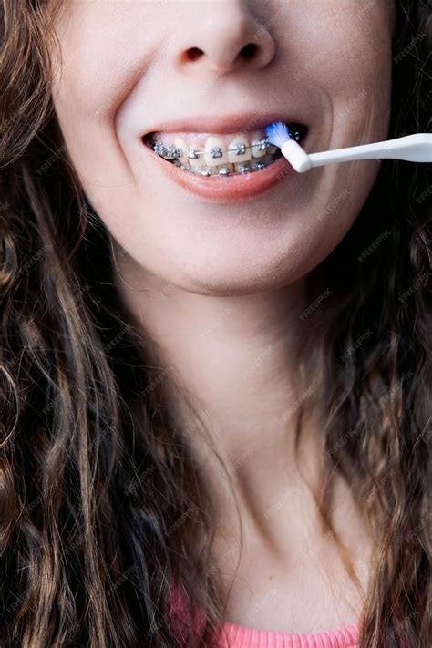 Young Woman Brushes Her Teeth With Braces With A Monobeam Brush Closeup Premium Photo