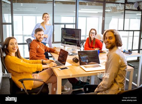 Portrait Of A Group Of Young Programmers Dressed Casually Working On Computer Code Sitting In