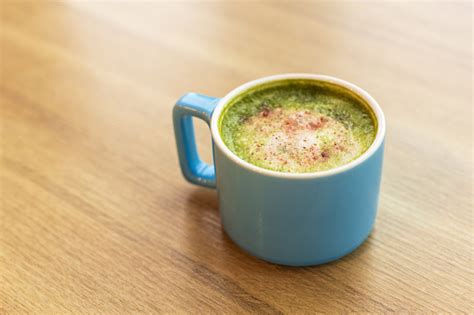 녹차 말차 라떼가 있는 블루 컵 동결 건조 딸기가 나무 테이블에 앉아 공간을 복사합니다 건강한 영양 개념 야채 또는 젖소 우유를