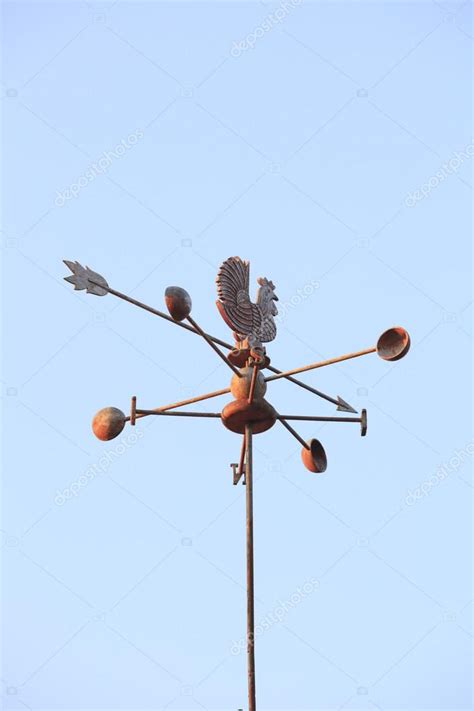 Weather Vane Compass Over House Roof Against Blue Sky Background Stock