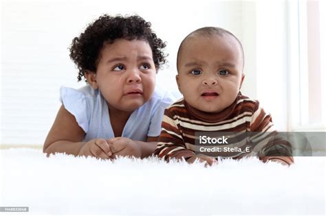 곱슬 머리를 가진 슬픈 작은 아프리카 계 미국인 소녀와 푹신한 흰색 양탄자에 누워있는 동안 우는 여동생 뺨을 따라 흐르는 눈물 방울 눈 분비물 화가 나고 성질이 나빠진 아이