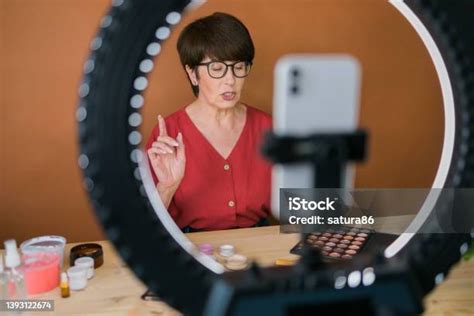중년 여성 뷰티 블로거 또는 집에서 방에서 비디오를 녹화하는 메이크업 제품 인플루언서 링 램프 및 스마트폰 사용 55 59세에 대한 스톡 사진 및 기타 이미지 Istock