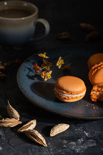 검은 색 콘크리트 배경에 커피 한 잔과 오렌지 마카롱 또는 마카롱 케이크 하드 라이트 대비 낮은 키 측면 보기 클로즈업 0명에