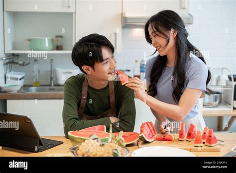 A Happy And Handsome Young Asian Man Is Being Fed A Slice Of Watermelon