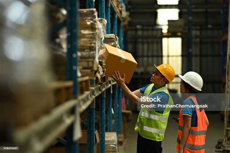 단단한 모자와 반사 재킷을 입은 두 명의 창고 직원이 창고의 선반에 상자를 적재하거나 하역합니다 체크리스트에 대한 스톡 사진 및 기타 이미지 Istock