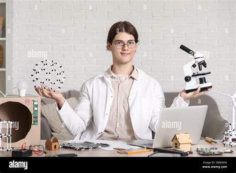 Male Inventor With Molecular Model And Microscope At Table In Office