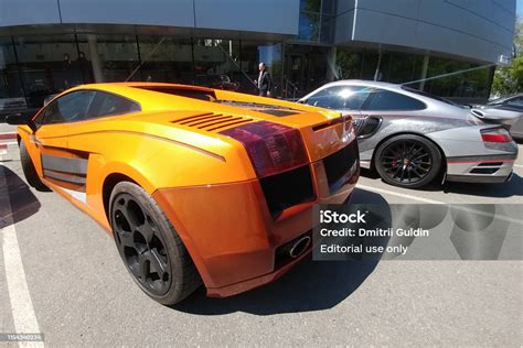 화려한 포 르 쉐 911 근처 거리에 주차 된 카본 후드와 다른 부품 들과 함께 하는 밝은 오렌지색 람보르기니 갈라도는에 어로 그래피와 피상적 인 튜닝이 있습니다