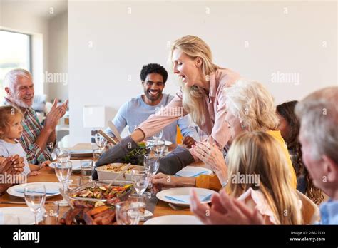 Mother Serving Food As Multi-Generation Family Meet For Meal At Home Stock Photo - Alamy