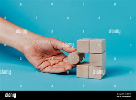 A Man Is Putting A Cylindrical Building Block In A Stack Of Rectangular