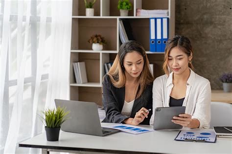 동료들 앞에서 프레젠테이션을 하는 여성 사업가 기업 그룹 교육에서 노트북과 금융 서류를 테이블 위에 올려놓은 재무 차트를 설명하는 여성 사업가 2명에 대한 스톡 사진 및