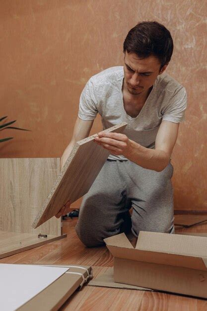 Premium Photo Man Assembling Furniture While Sitting On Floor With Wooden Plank From Table