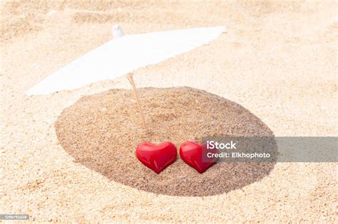 황금 빛 모래에 해변 우산 아래 두 빨간 마음 세인트 발렌타인 데이와 2 월 14 일 개념 사랑 커플 컨셉에 대한 낭만적 인 여행 사랑 단합 결혼 0명에 대한 스톡 사진 및