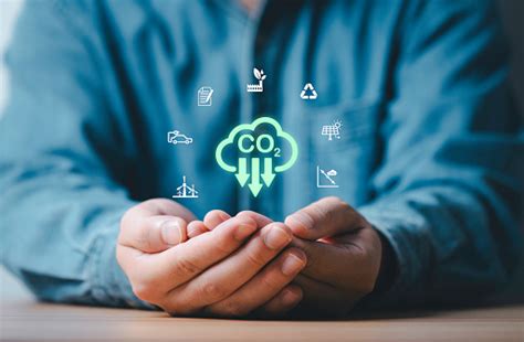 환경 아이콘이 있는 탄소 감축 표지판을 들고 있는 사업가는 녹색 공장 탄소 발자국을 위한 전기 자동차 재활용 기후 변화로 인한 지구 온난화를 제한하기 위한 탄소 배출권 등을