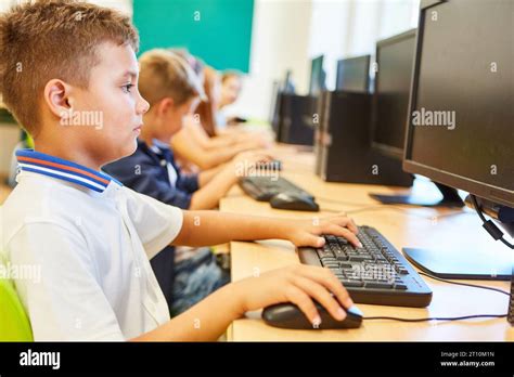 Side View Of Schoolboy Looking At Computer Screen Sitting At Desk In