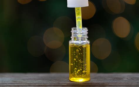 밝은 조명의 노란 오일의 오일 드롭퍼 병 거품은 초점이 흐린 배경과 대조적입니다 화학 과학에 대한 스톡 사진 및 기타 이미지 화학 과학 0명 건강관리와 의술 Istock