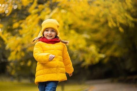 행복한 가을 시간 아름다운 가을 날에 공원에서 야외에서 달리는 노란 코트 모자 빨간 스카프를 입은 사랑스러운 웃음 어린 소녀 텍스트공간을 복사합니다 10월에 대한 스톡 사진