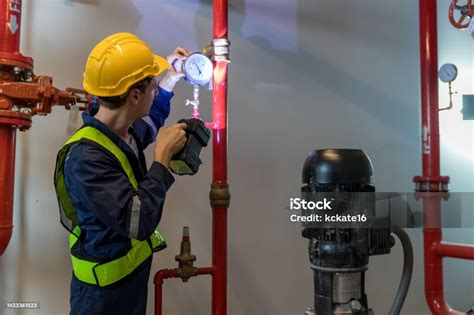 화재 진압 시스템 및 화재 장비를 점검하는 엔지니어 또는 기술자 작업 엔지니어는 물 스프링클러 배관 및 화재 경보 제어 시스템에 대한 빨간색 발전기 펌프를 확인합니다 불에