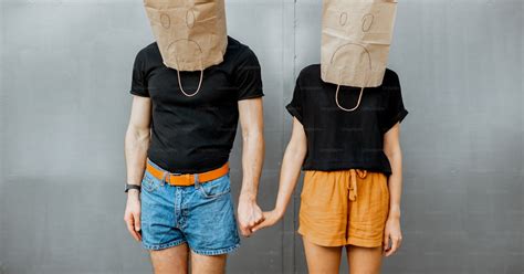 머리에 종이 봉지를 들고 회색 벽 배경에 손을 모으고 있는 젊은 부부의 초상화 사진 Unsplash의 우크라이나 이미지