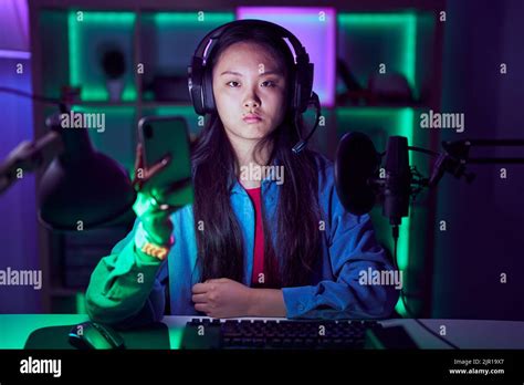 Young Asian Woman Playing Video Games With Smartphone Skeptic And Nervous Frowning Upset