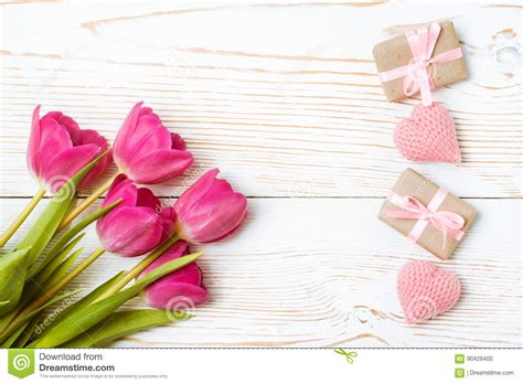 Букет тюльпанов обернутых подарков и связанных сердец на белой деревянной предпосылке Стоковое