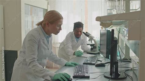 Two Multiethnic Male And Female Scientists Wearing White Lab Coats And