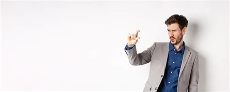 Empresario tratando de ver algo pequeño que muestra el tamaño de una cosa pequeña con los dedos