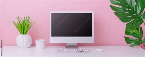 A Modern Workspace Featuring A White Computer Monitor Keyboard And Mouse Against A Pink Wall