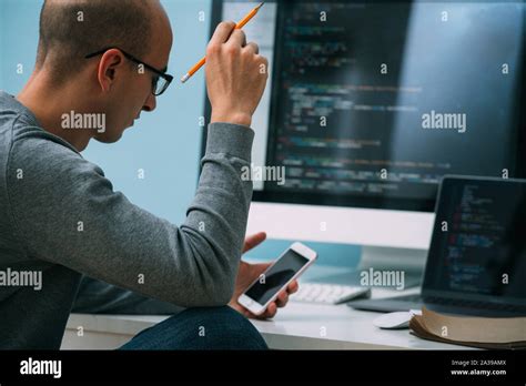 Programmer Working Behind The Desk Analysing Code On The Black Screen
