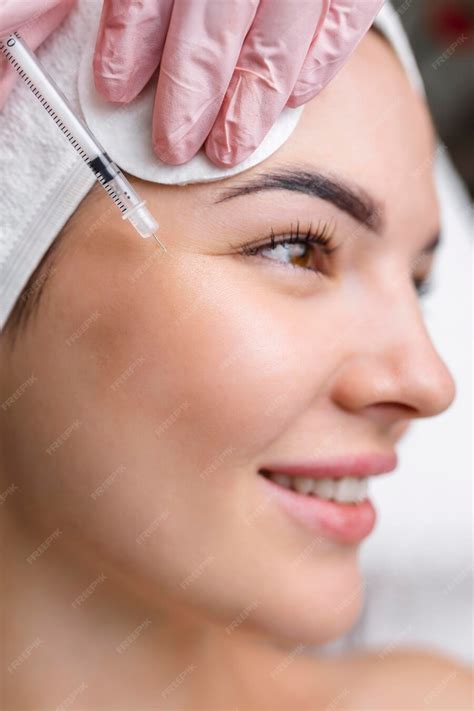 Feche As Mãos Do Jovem Cosmetologista Injetando Botox No Rosto Feminino