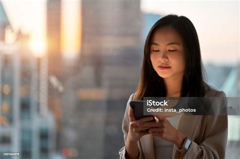 젊은 아시아 전문 사업가가 사무실 창구에 서 있는 전화기를 사용한다 20 24세에 대한 스톡 사진 및 기타 이미지 20 24세 경영자 금융 Istock