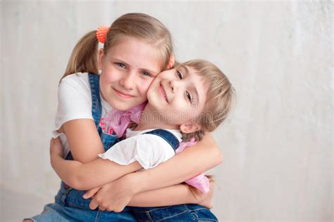 2 прелестных маленьких сестры смеясь над и обнимая одином другого Стоковое Фото изображение