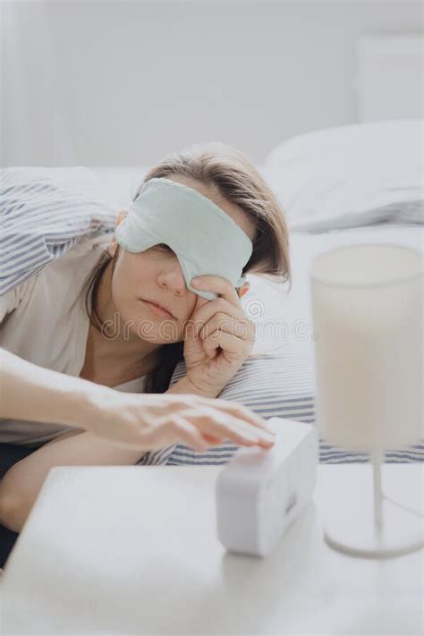 Woman In Bed With A Sleep Mask Wakes Up And Turns Off The Alarm A Clock With A Timer A Woman