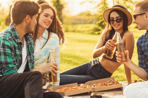 화창한 날에 공원에서 피크닉을 즐기고 맥주 음료를 마시고 화창한 여름날에 잔디에 앉아있는 피자를 먹는 친구들 건강에 좋지 않은 음식에 대한 스톡 사진 및 기타 이미지