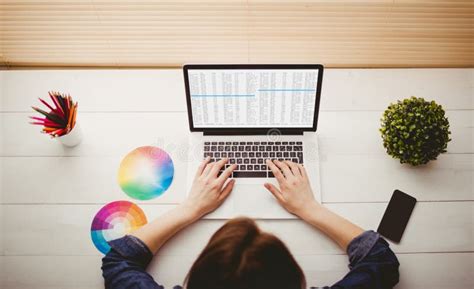 Caucasian Female Programmer Sitting At Desk With Color Charts Using Laptop With Coding On