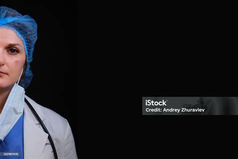 파란 의학 베레모에 마스크에서 상처와 상처를 가진 의사 텍스트 공간을 복사합니다 어두운 배경에 있는 간호사는 얼굴에 보호복의 흔적을 입고 클로즈업합니다 개념 코로나바이러스