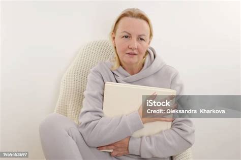 밝은 색의 운동복에서 무언가를 기억하는 꿈을 꾸는 앨범을 껴안는 여자 흰색 베이지색 페이지가 있는 앨범을 손에 들고 광고를 위한 빈 공간을 엽니다 꿈을 기다리는 머리카락을