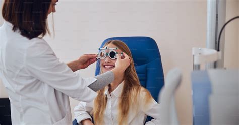 현대 안과 클리닉에서 시력 검사를 위한 시험 프레임을 검사하는 의사의 동안 약 의자에 앉아 캐주얼한 옷을 입은 예쁜 아가씨 사진 Unsplash의 사진술 이미지