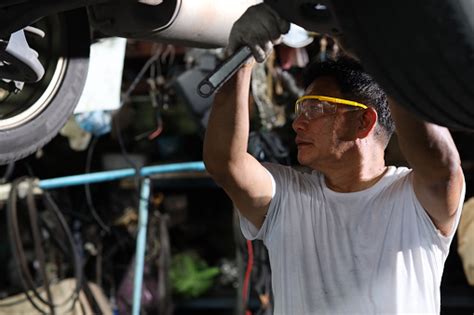 남자 기술자 자동차 정비사는 반쯤 제복을 입고 정비를 점검하고 수리 차고 역에서 리프트 자동차 서비스를 제공합니다 렌치를 들고 고장 차량을 고치는 작업자는 웃으며 카메라를