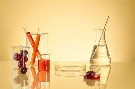 정면에서 노란색 배경의 실험실 장면 테이블에는 투명한 유체 삼각 플라스크 시험관 붉은 액체와 신선한 체리가 담긴 비커 빈 연단과 같은 실험실 항목이 표시되었습니다 0명에