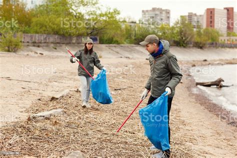 쓰레기 피커와 비닐 봉지를 사용하여 해안의 해변을 청소하는 두 명의 환경 운동가 젊은 남성과 여성 30 34세에 대한 스톡 사진 및 기타 이미지 Istock