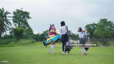 아시아의 남녀 어린이들이 골프 연습장에서 프로 선수들에게 골프를 배우고 있다골프채와 드라이버를 위한 훈련골프백을 들고 골프장으로
