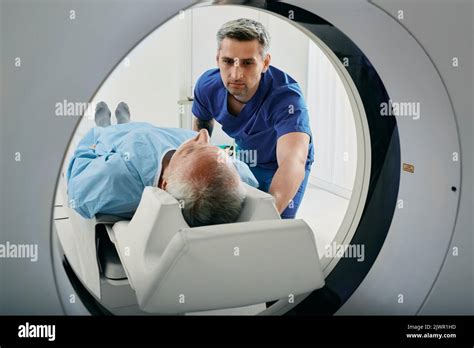 Senior Man Going Into Ct Scanner Ct Scan Technologist Overlooking Patient In Computed